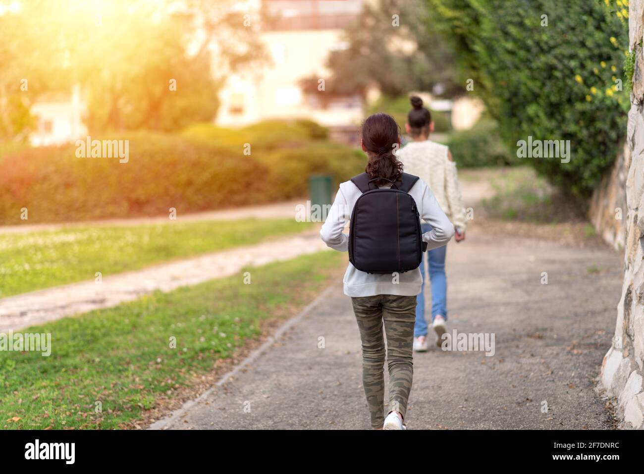Two little girl with a backpack going to school. Two teenager travel ...