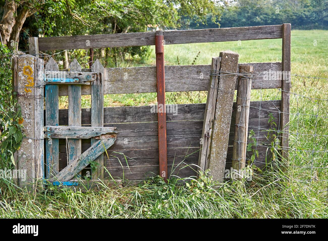Old repaired closed fence made from wood, steel and concrete in the ...