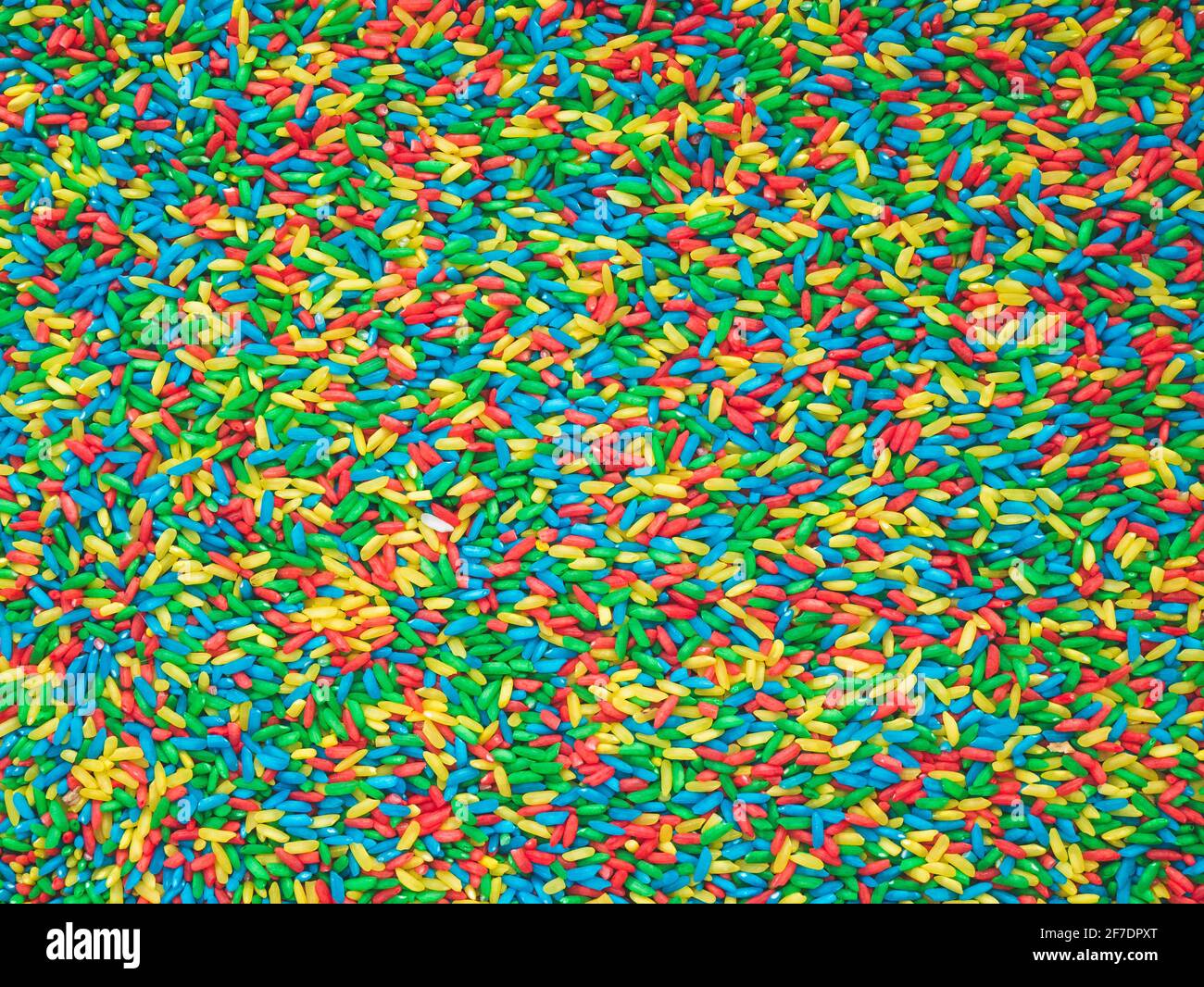Texture of colored rice. Grain of red, green, yellow and blue colors ...