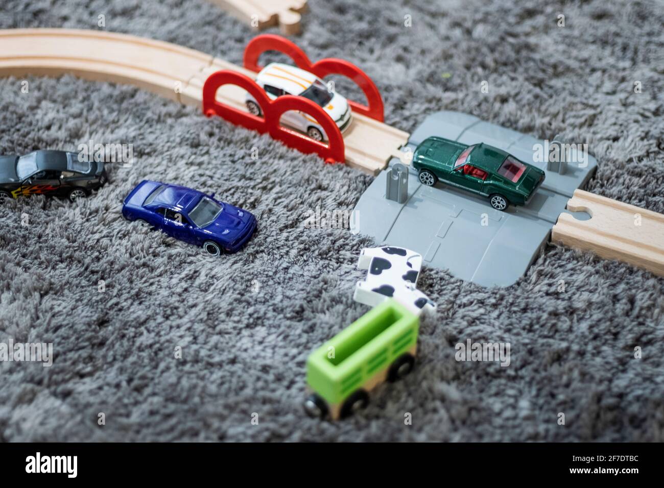 Tiny metal toy cars on a grey carpet floor with wooden railway ...