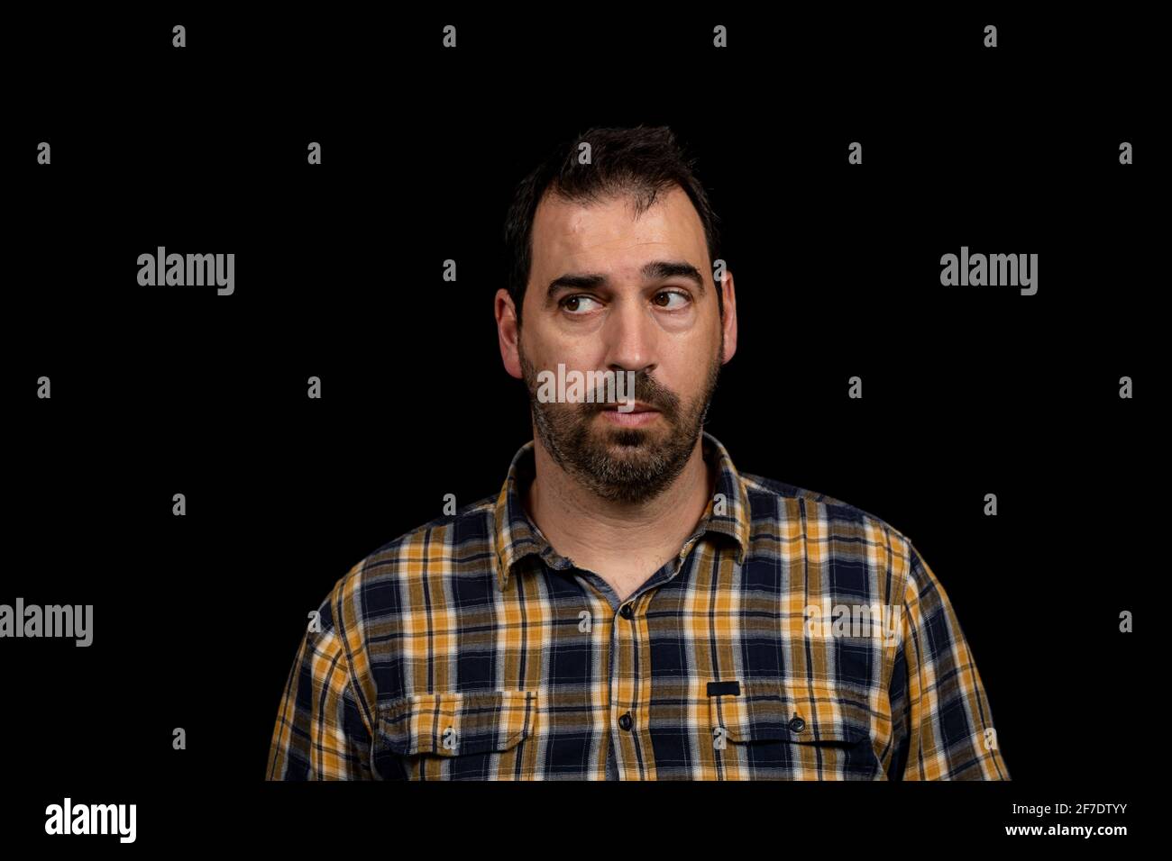 Portrait of bearded man in yellow checkered on black studio background ...