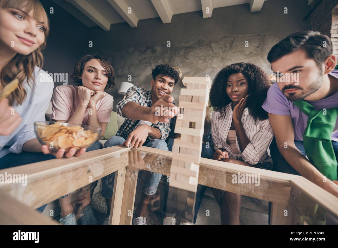 Portrait of attractive cheerful friends playing brick game pastime team ...