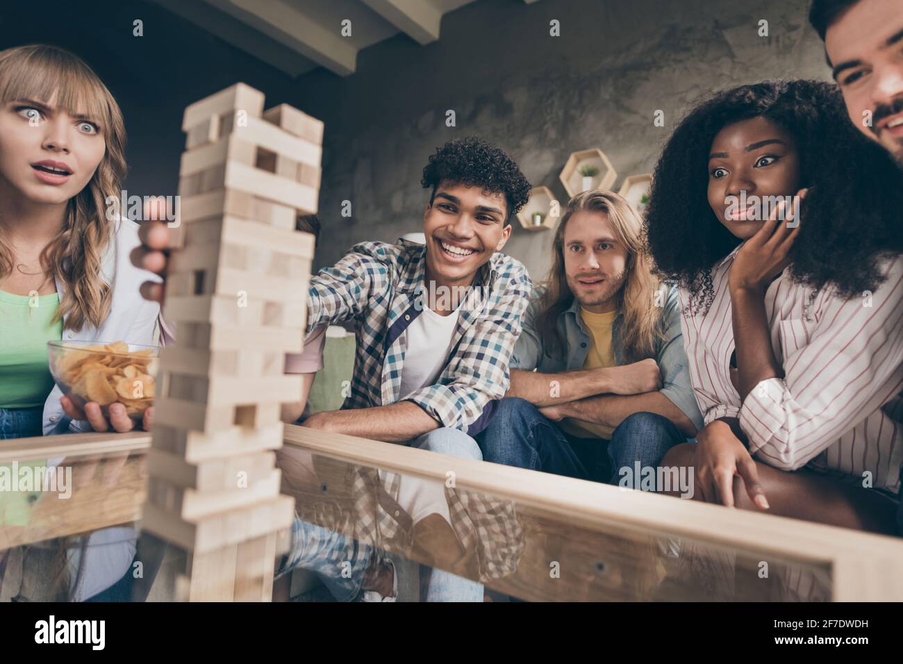 Portrait of attractive cheerful friends gathering playing brick game ...