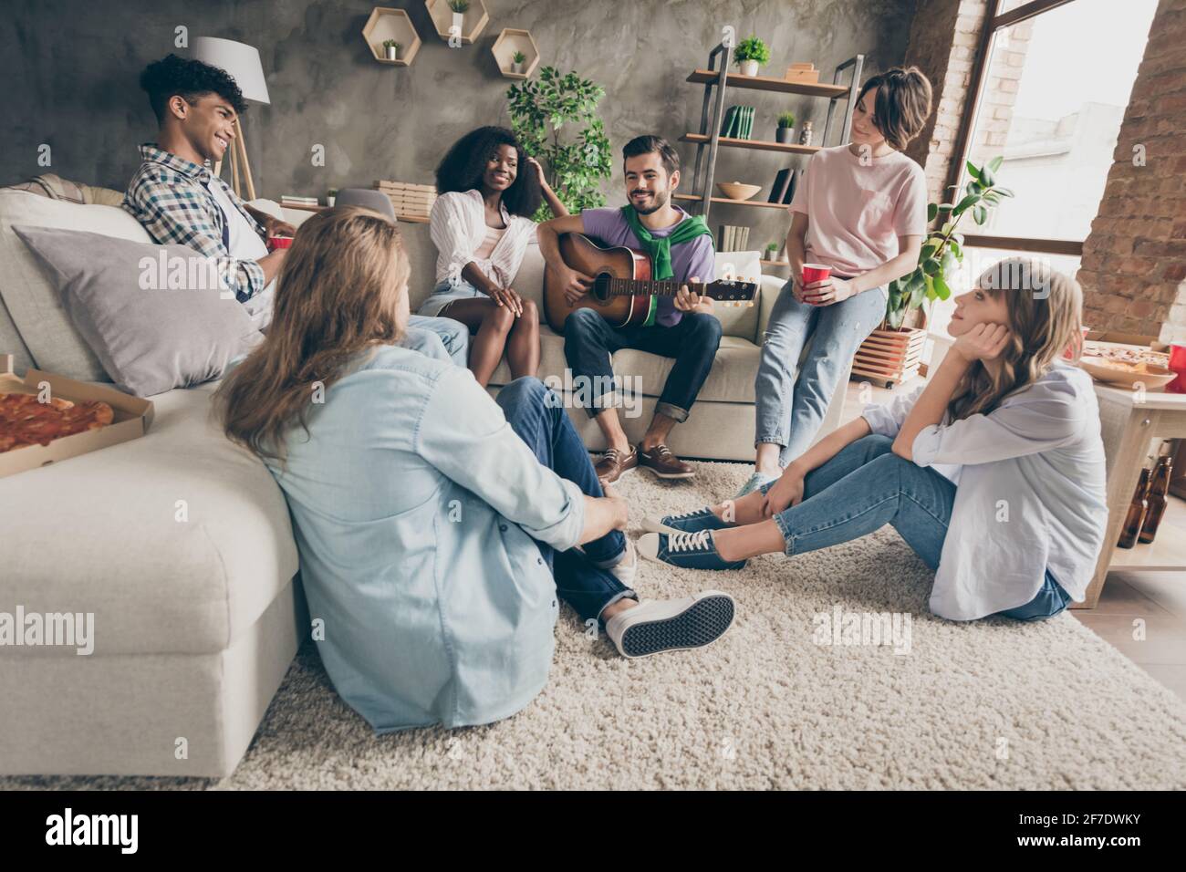 Portrait of attractive cheerful friends gathering playing guitar having ...