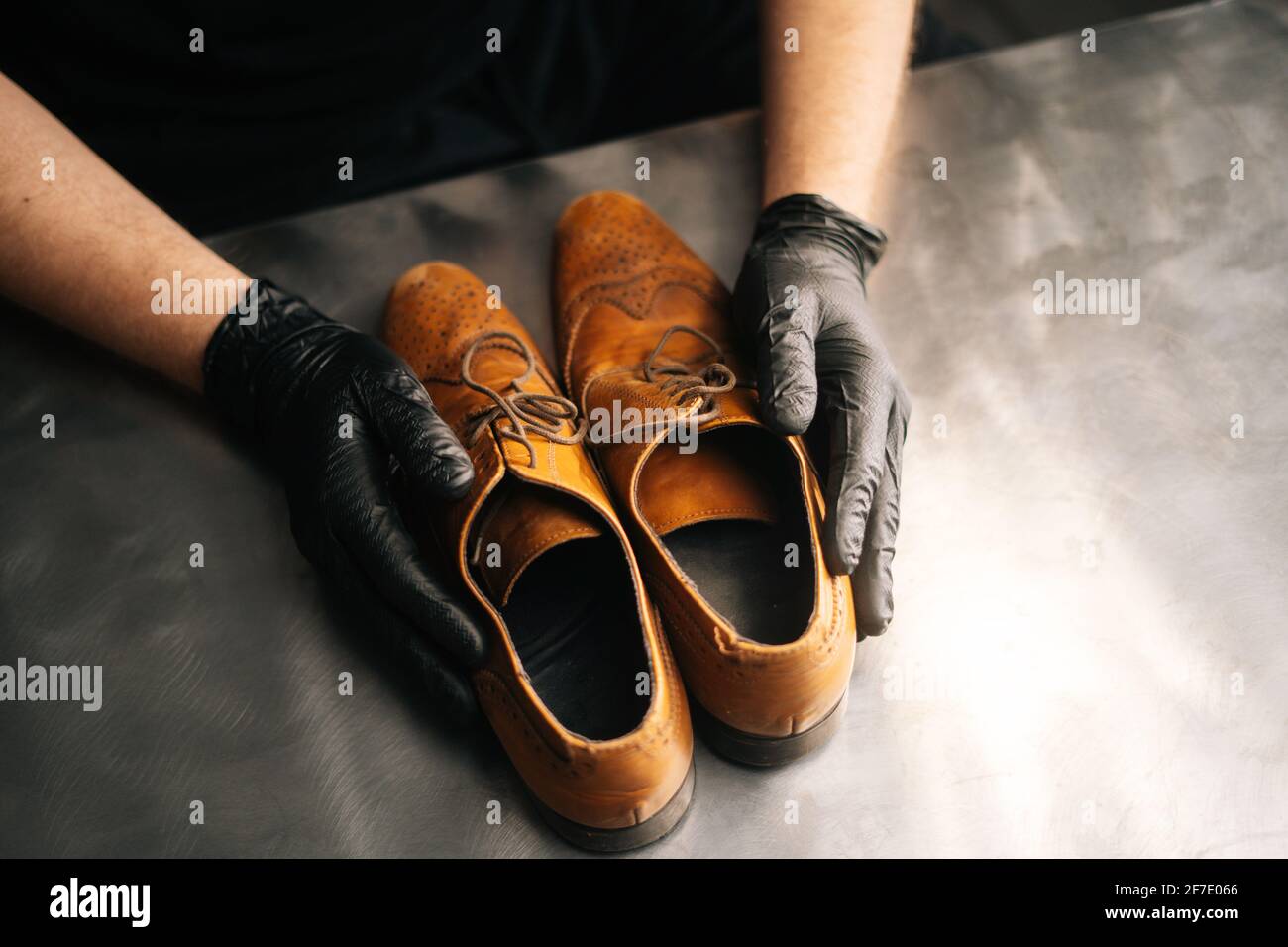 Close-up top view of hands of shoemaker shoemaker in black gloves ...