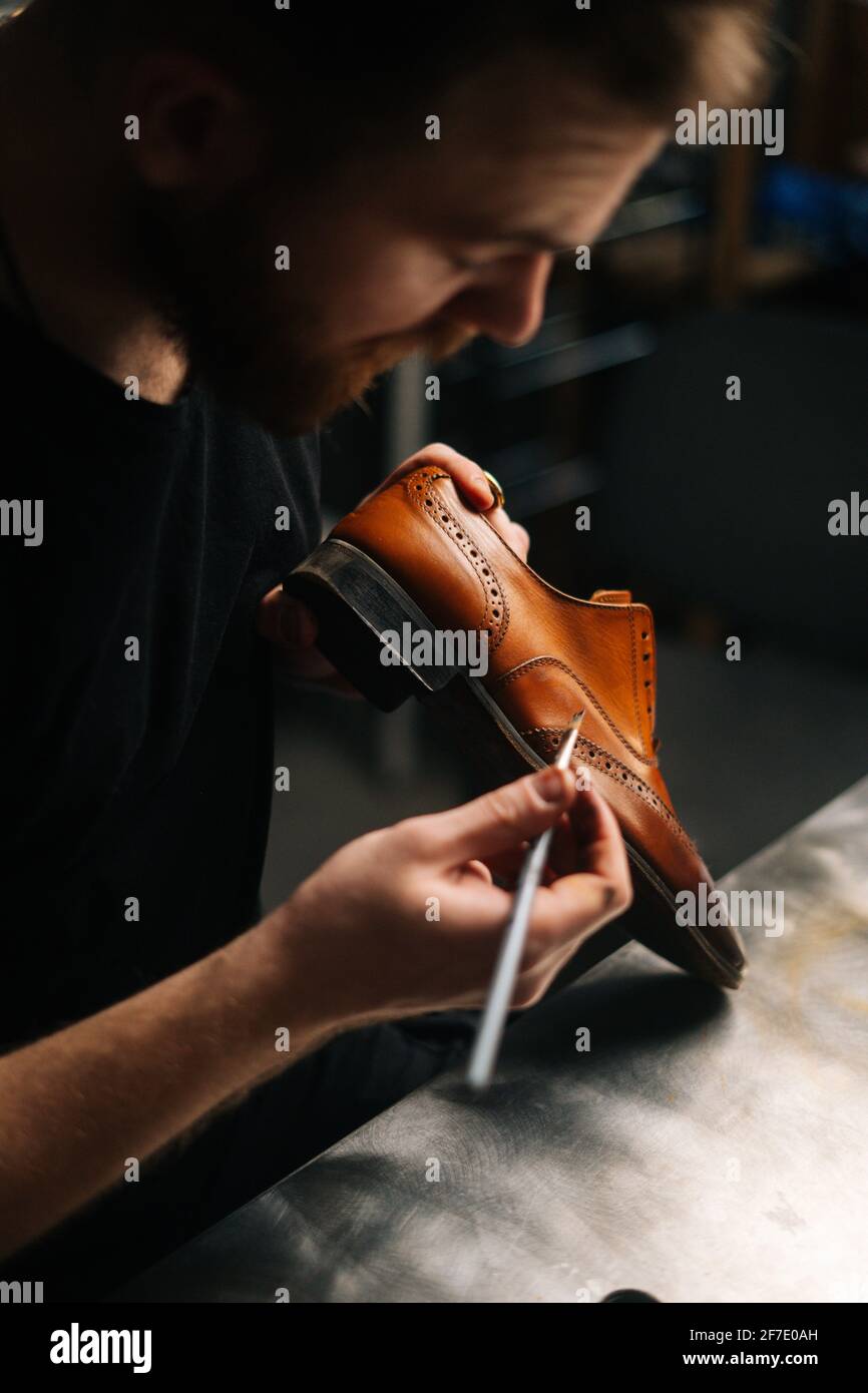 Top view of shoemaker painting heel and sole of light brown leather ...
