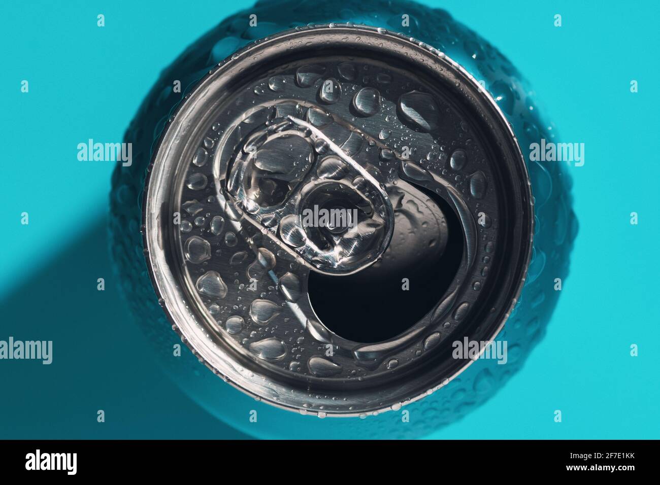Cyan blue open soda can in shadow and light covered with water drops ...