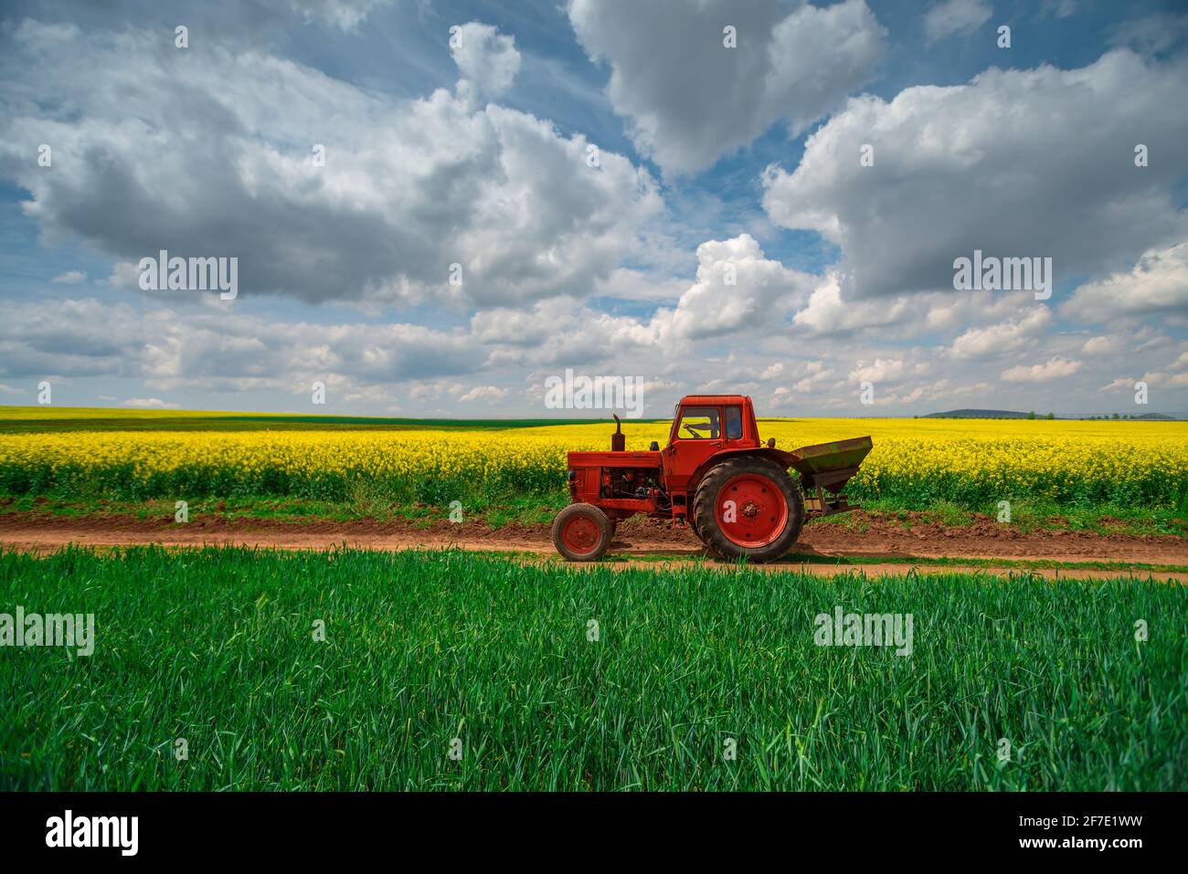 Red tractor in a field and dramatic clouds Stock Photo - Alamy