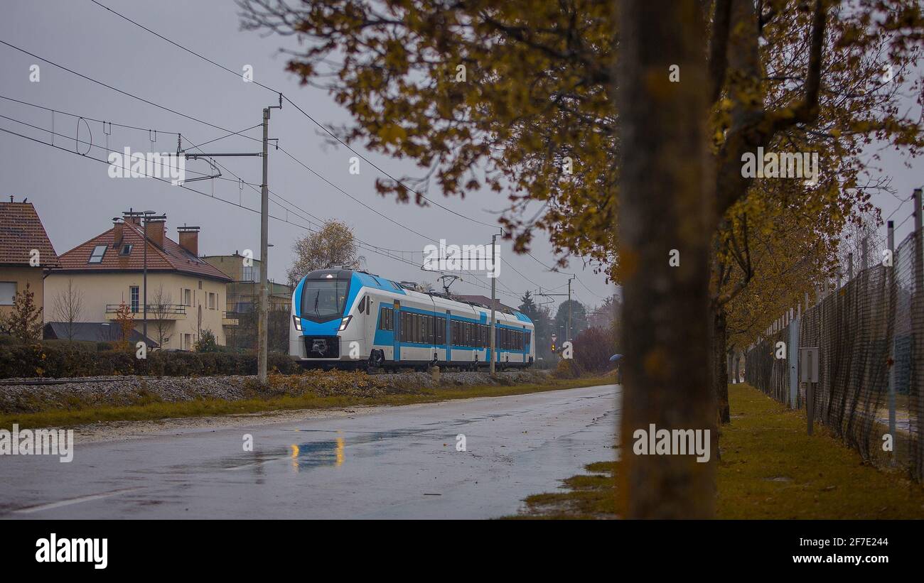 Modern white and blue passenger commuter train passing by in rain ...