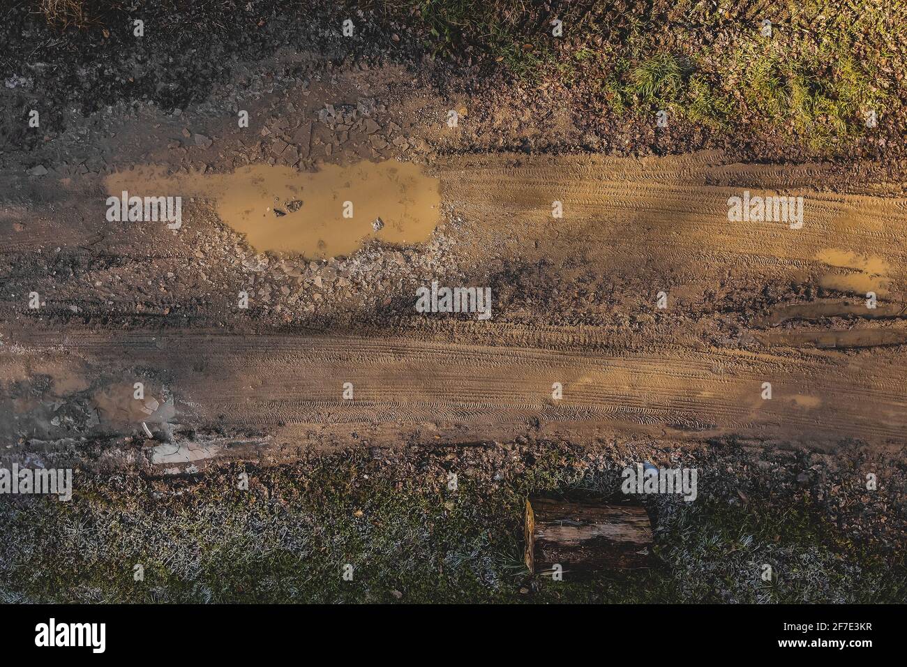 Mud and puddles seen from above, rough muddy terrain with visible tire ...