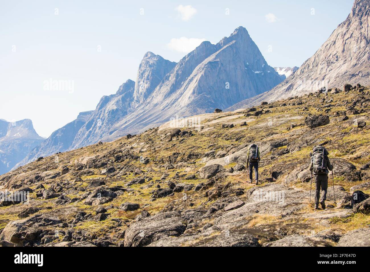 Two backpackers traverse an open talus slope below dramatic mountains ...