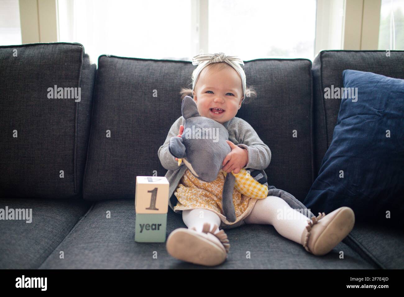 One year old girl sitting on couch with wooden blocks and stuffy Stock ...