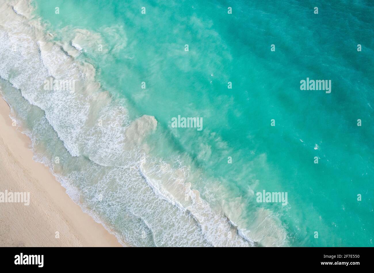 Aerial shot of the bright turquoise Hawaii ocean meeting the shore ...
