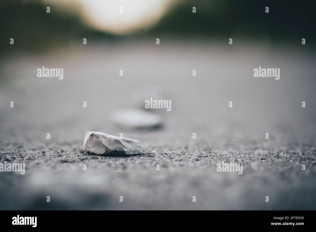 A sharp stone on a asphalt surface of a road. Detail photo of a sharp ...