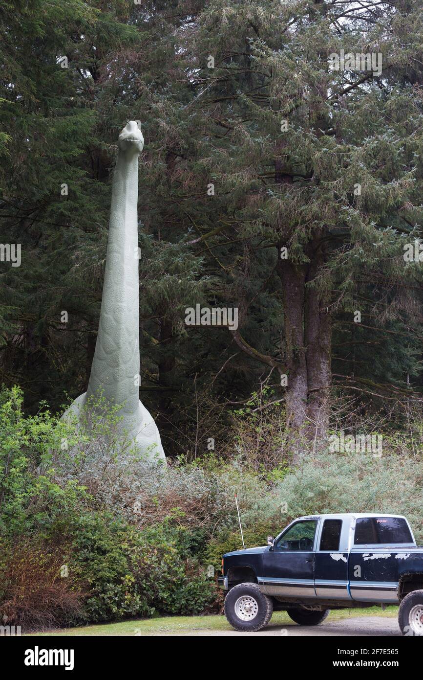 A brontosaurus statue appears to be emerging from the forest next to a ...