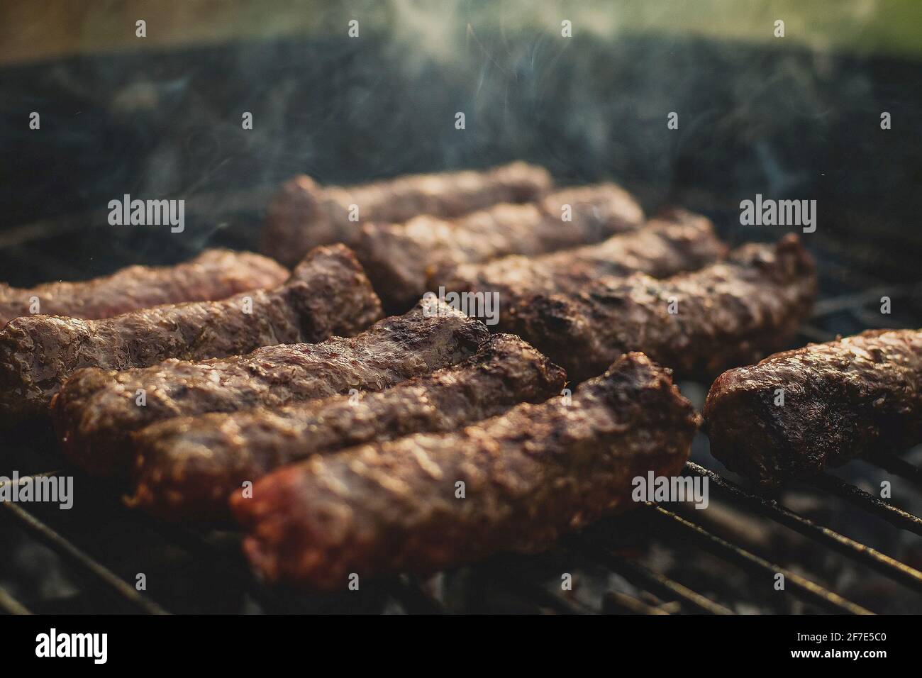 Detail of a fresh batch of meat on a small round grill with charcoal ...