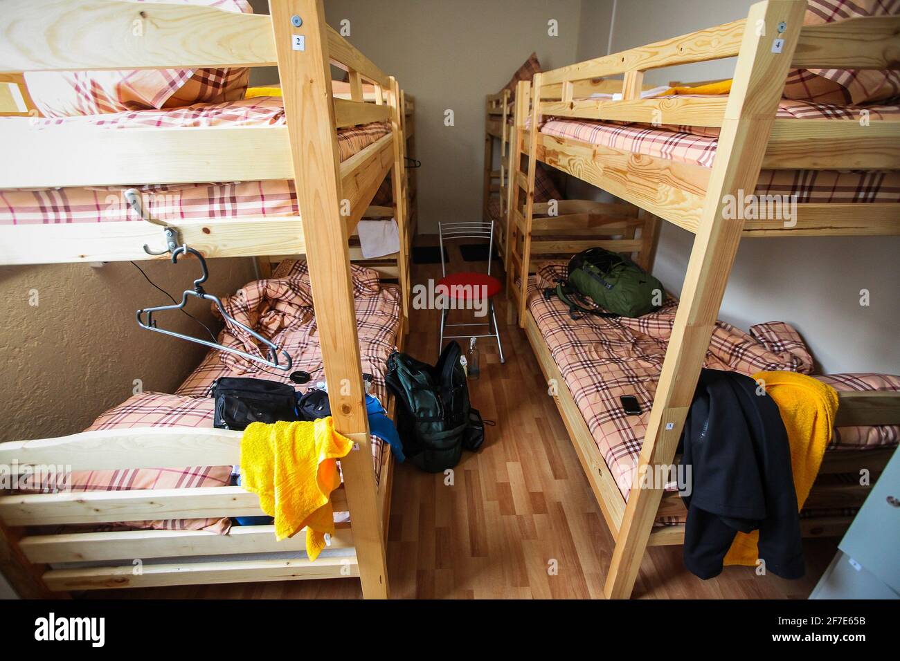 Interior of a cheap hostel room. Bunk beds, linen, backpacks, a chair ...