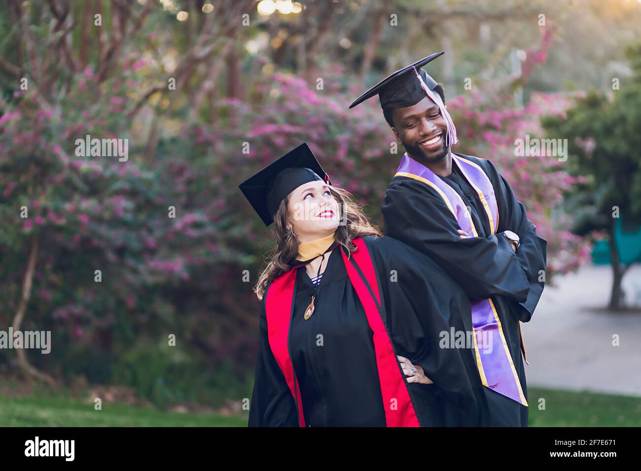 Young man & woman graduating college, wearing a graduation gown/cap ...