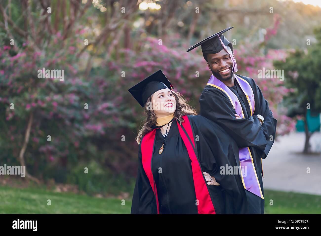 Young man & woman graduating college, wearing a graduation gown/cap ...