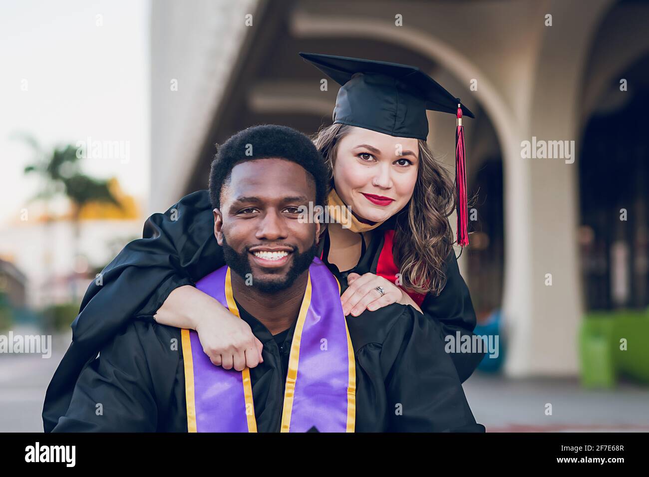 Young man & woman graduating college, wearing a graduation gown/cap ...