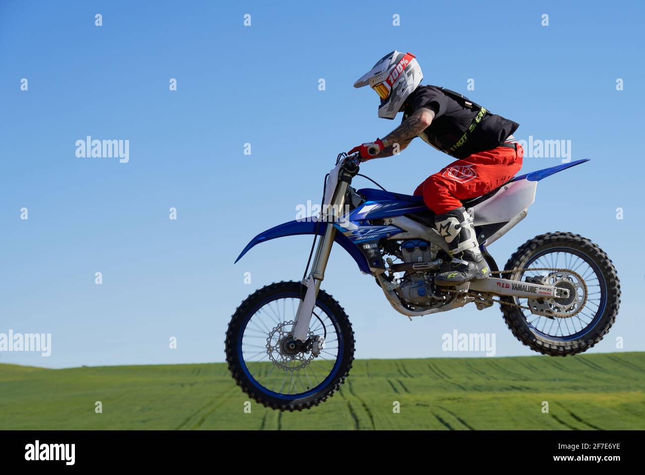 Side view of man performing stunt with motorcycle on motocross t Stock ...