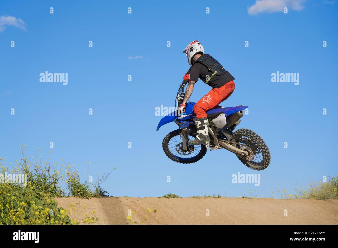Side view of man performing stunt with motorcycle on motocross t Stock ...