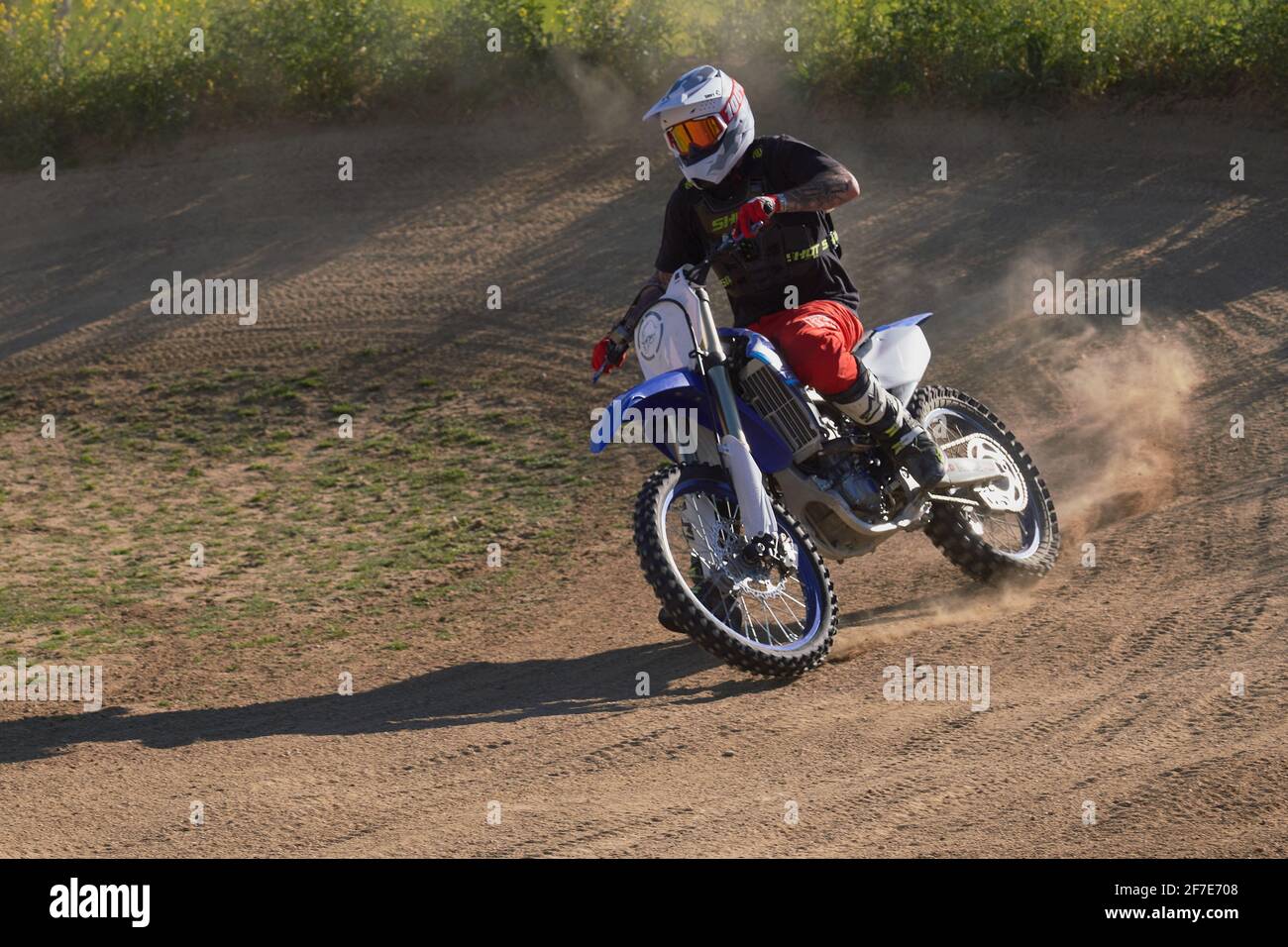 Side view of man performing stunt with motorcycle on motocross t Stock ...