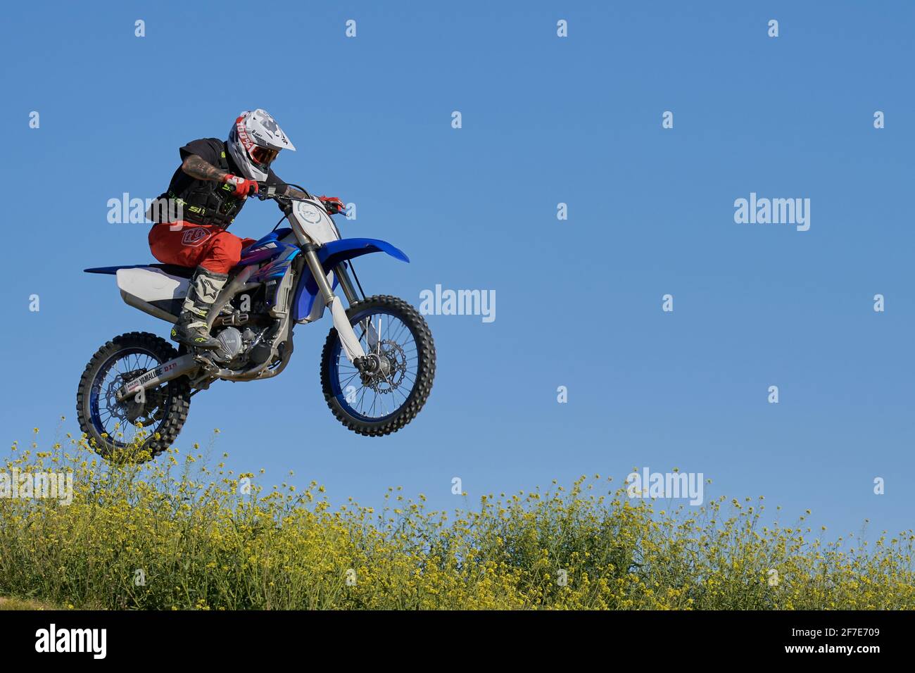 Side view of man performing stunt with motorcycle on motocross t Stock ...
