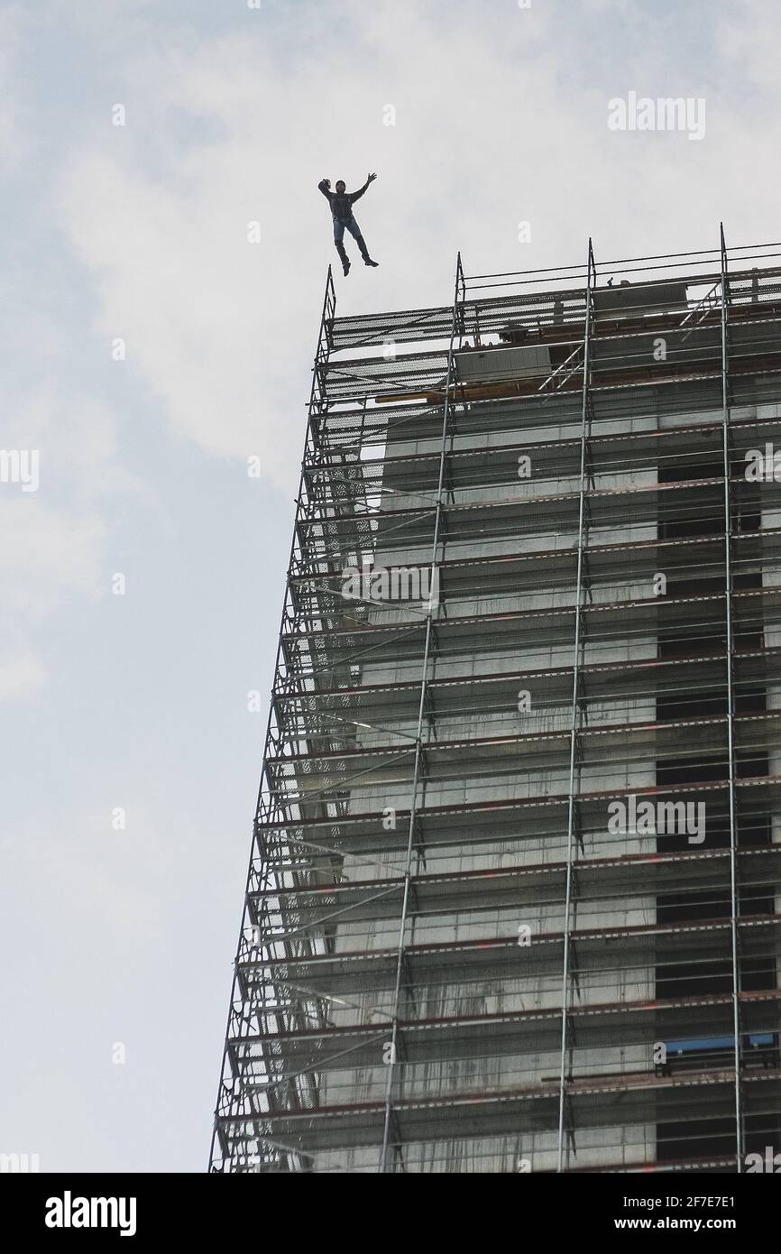 Silhouette of a person jumping from the top of a building that is still ...