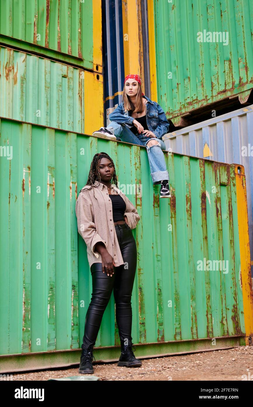 Two women wearing urban clothing surrounded by shipping containers ...