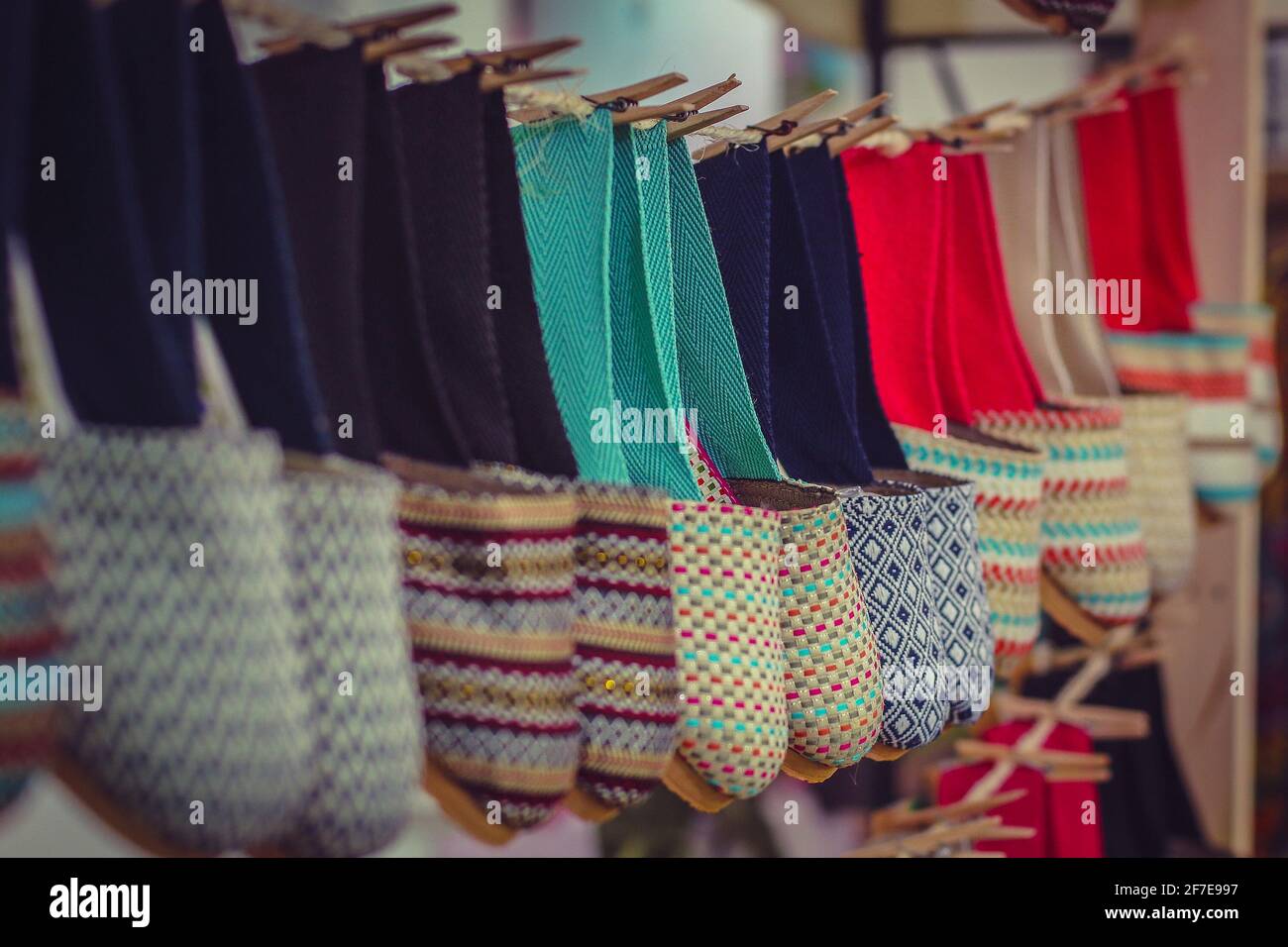 A row of wowen or knitted slippers hanging on a rope with pegs at an ...