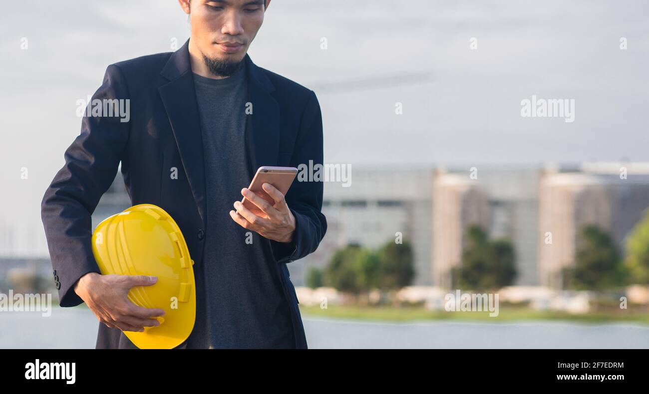 Worker man Engineer hold yellow hard hat use call phone outdoor site ...