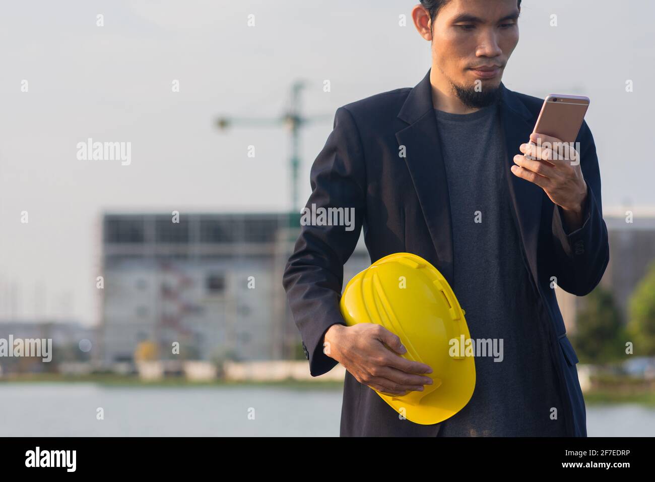Worker man Engineer hold yellow hard hat use call phone outdoor site ...