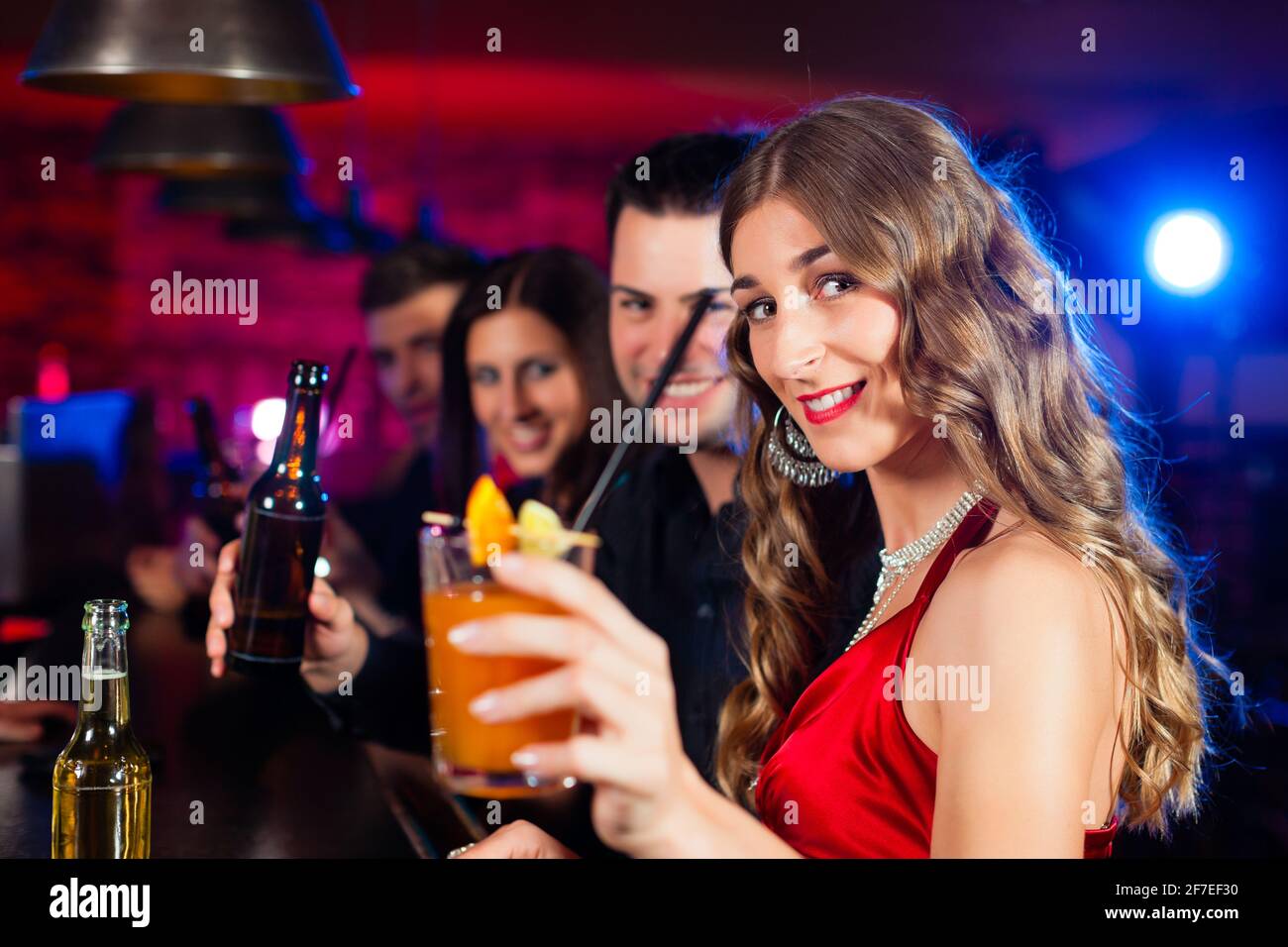 Group of party people with cocktails in a bar or club having fun; one ...