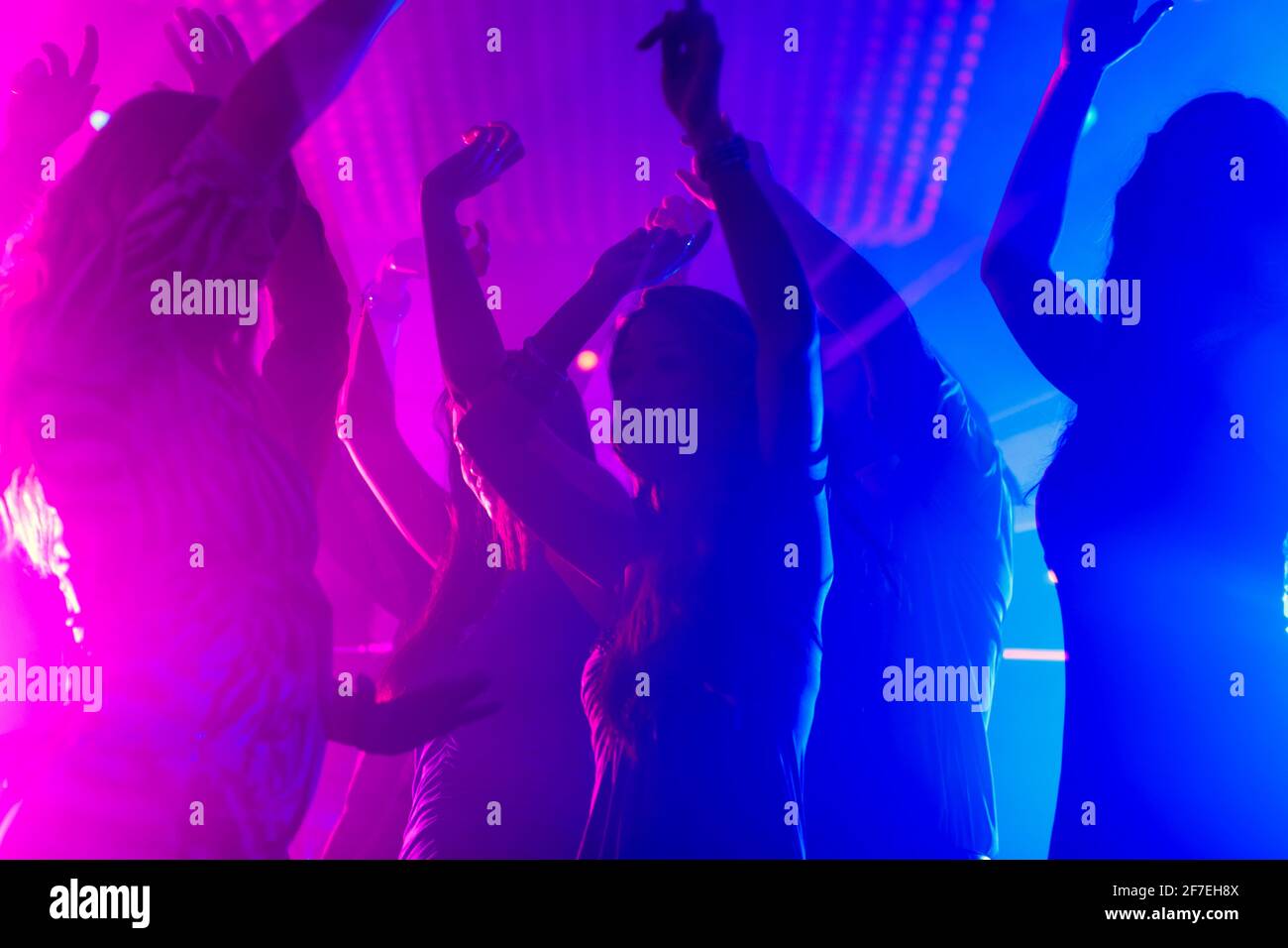 Group of party people - men and women - dancing in a disco club to the ...