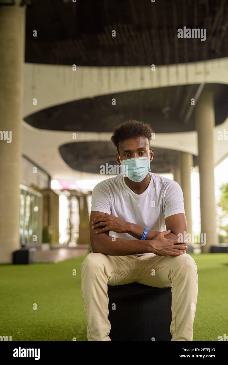 Handsome black African man sitting wearing face mask Stock Photo - Alamy
