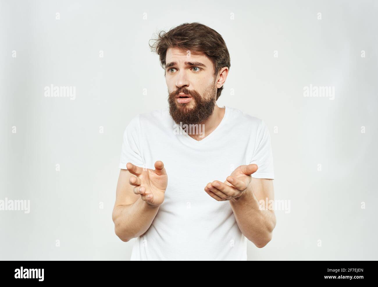 The man looks ahead in a puzzled way on a light background of emotions ...