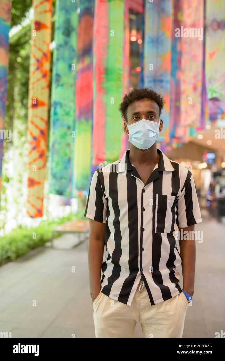 Portrait of handsome black African man wearing face mask in shopping ...