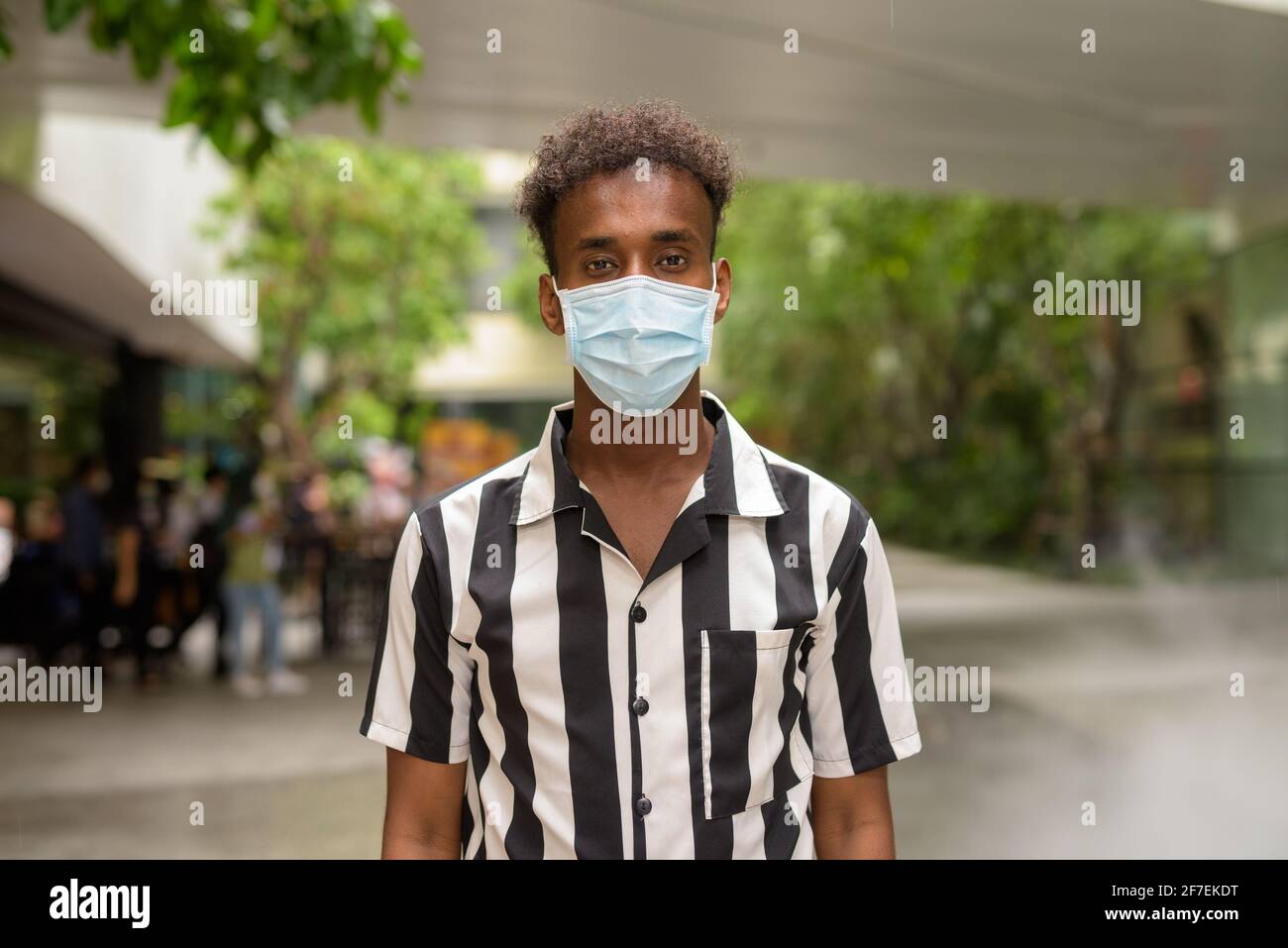 Portrait of handsome black African man wearing face mask outdoors in ...