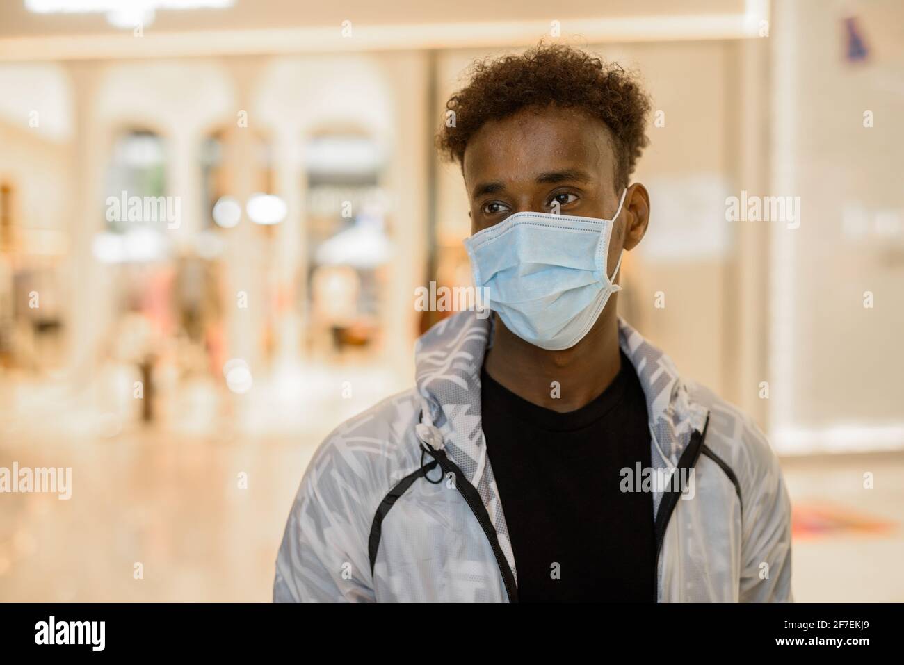 Portrait of handsome black African man wearing face mask in shopping ...