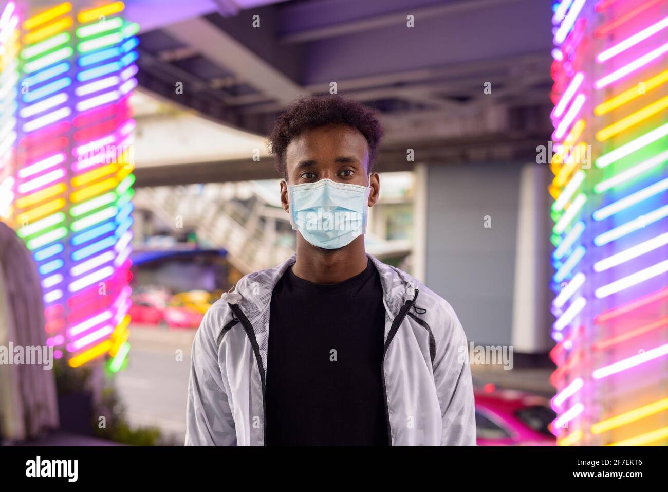 Portrait of handsome black African man wearing face mask with cool ...