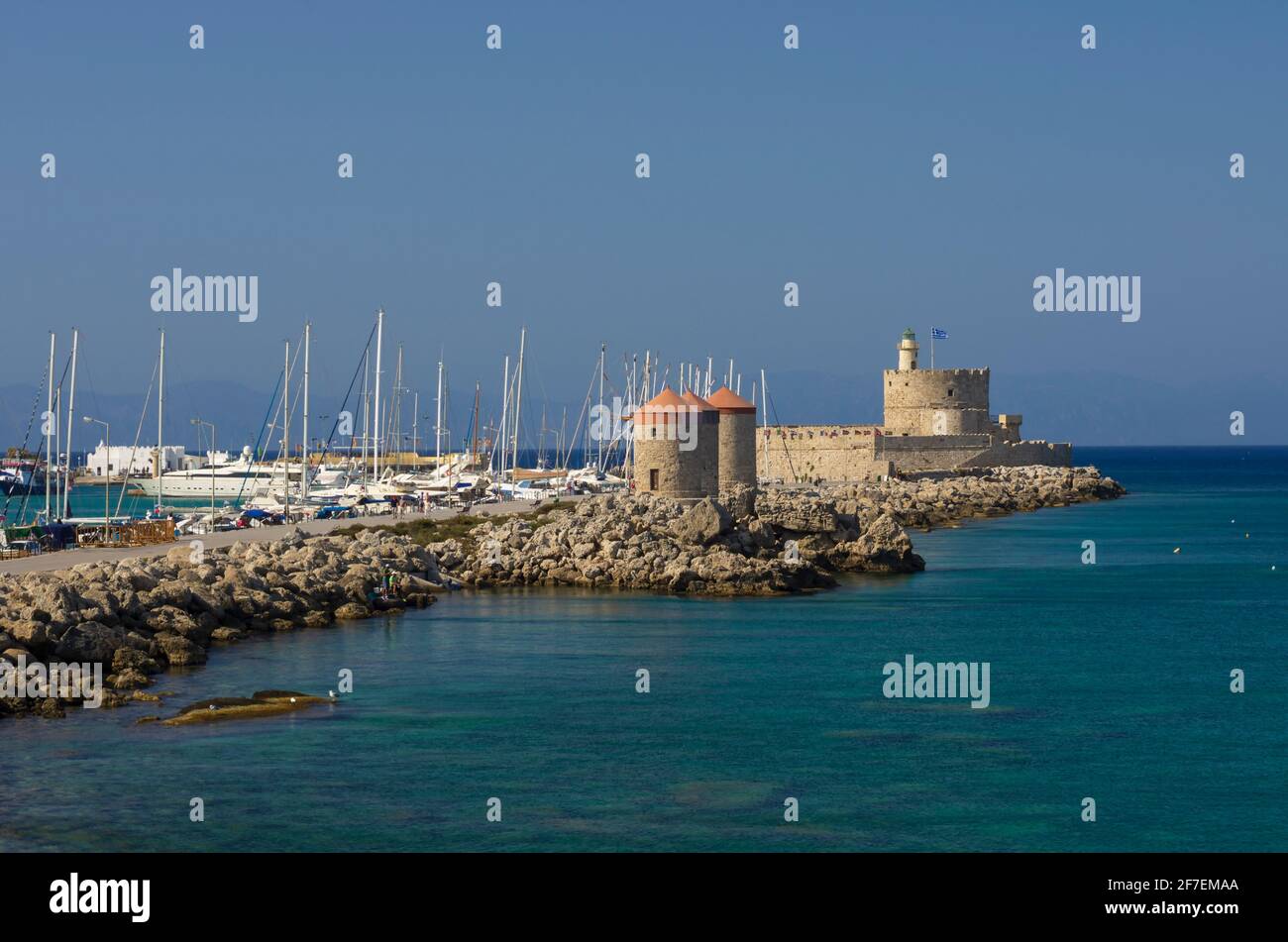 Seascape with a medieval fort and three windmills on a stone pier ...