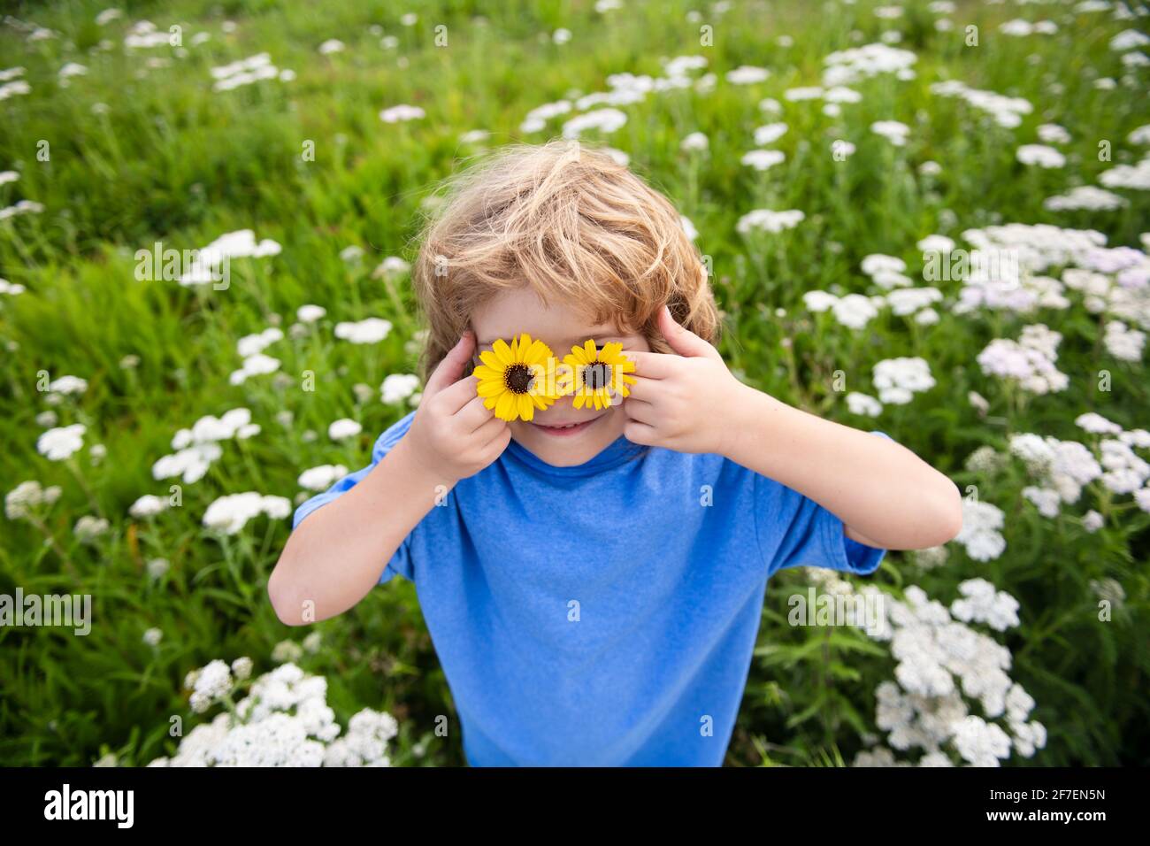 Spring kid. Funny little boy with daisy in eyes Stock Photo - Alamy