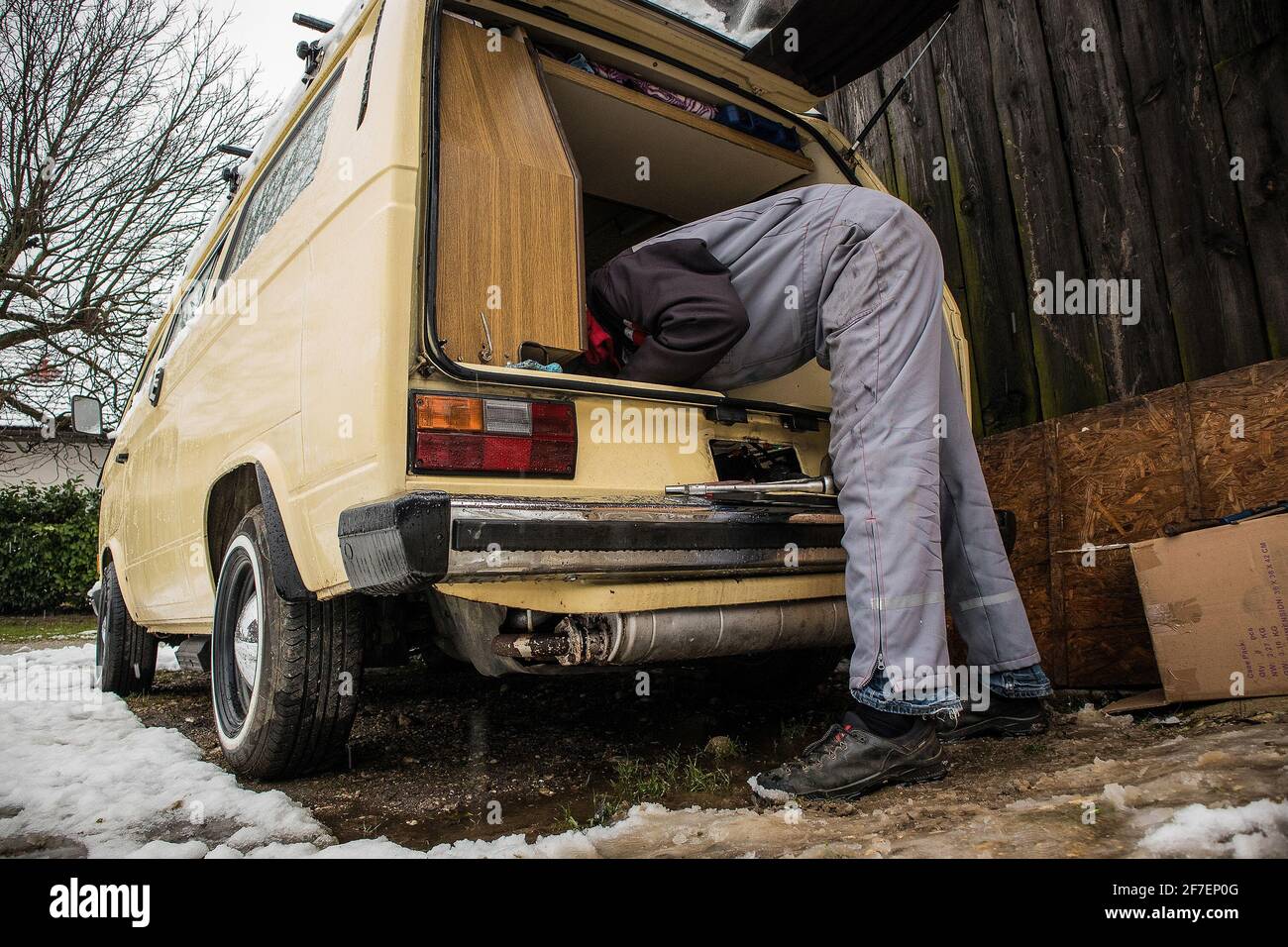 A person is fixing a van or a camper. A mechanic sticking his head into ...