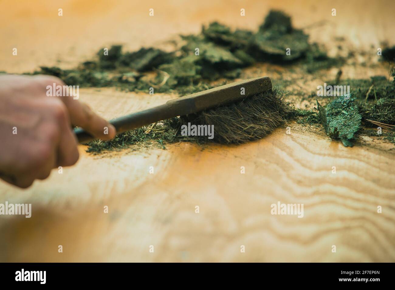 Cleaning grass debris from table with a small old broom after servicing ...