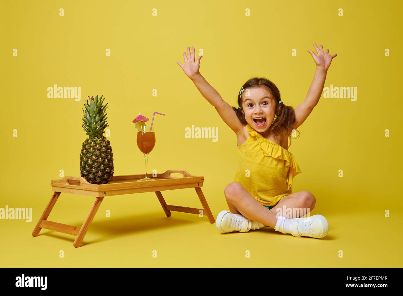 Adorable little girl raising her arms up and expressing happiness while ...