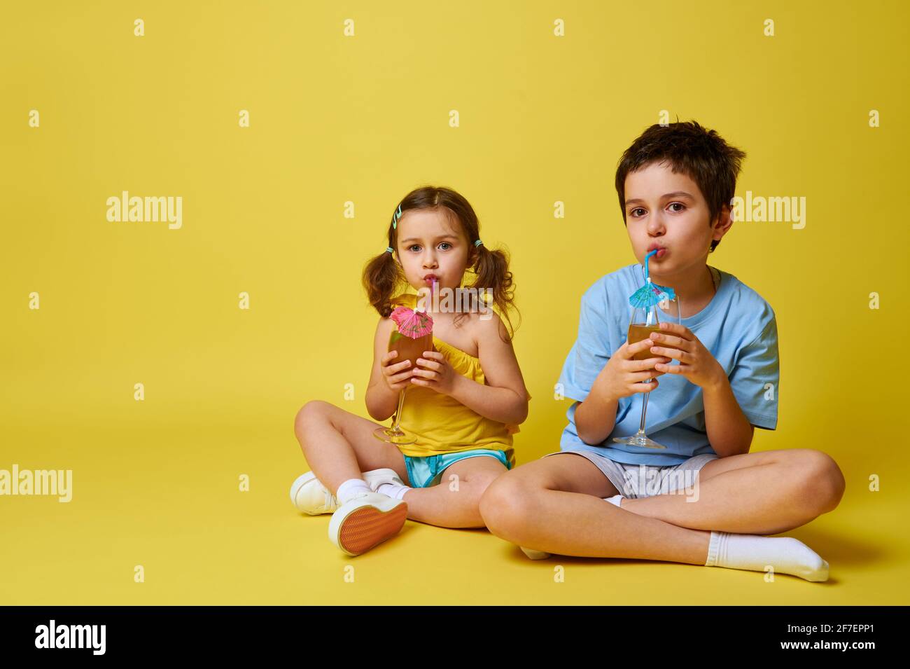 Cute children, boy and girl drinking from a straw a delicious cocktail ...