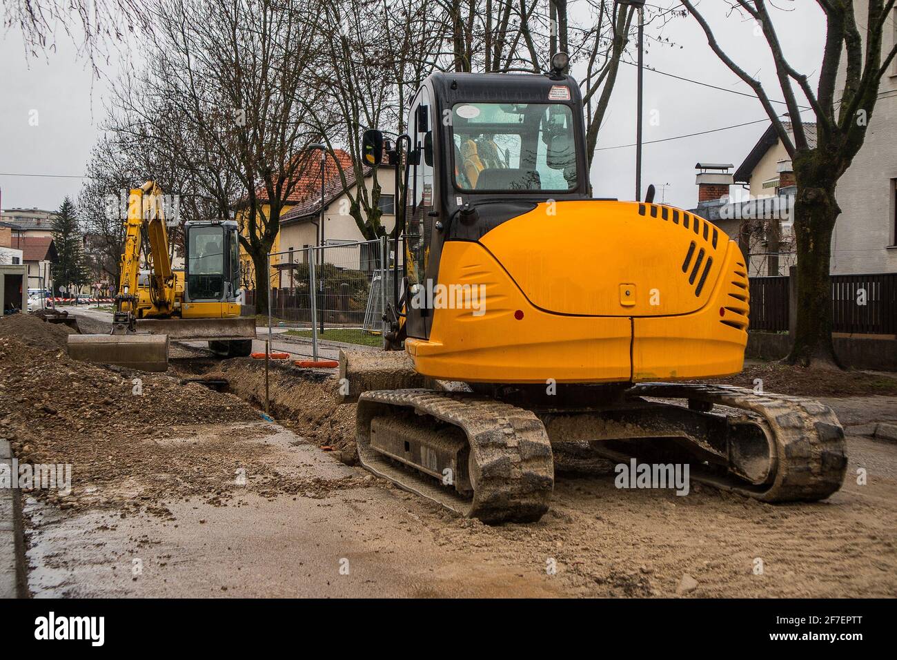 Construction site on a city street. Two yellow diggers or excavators ...