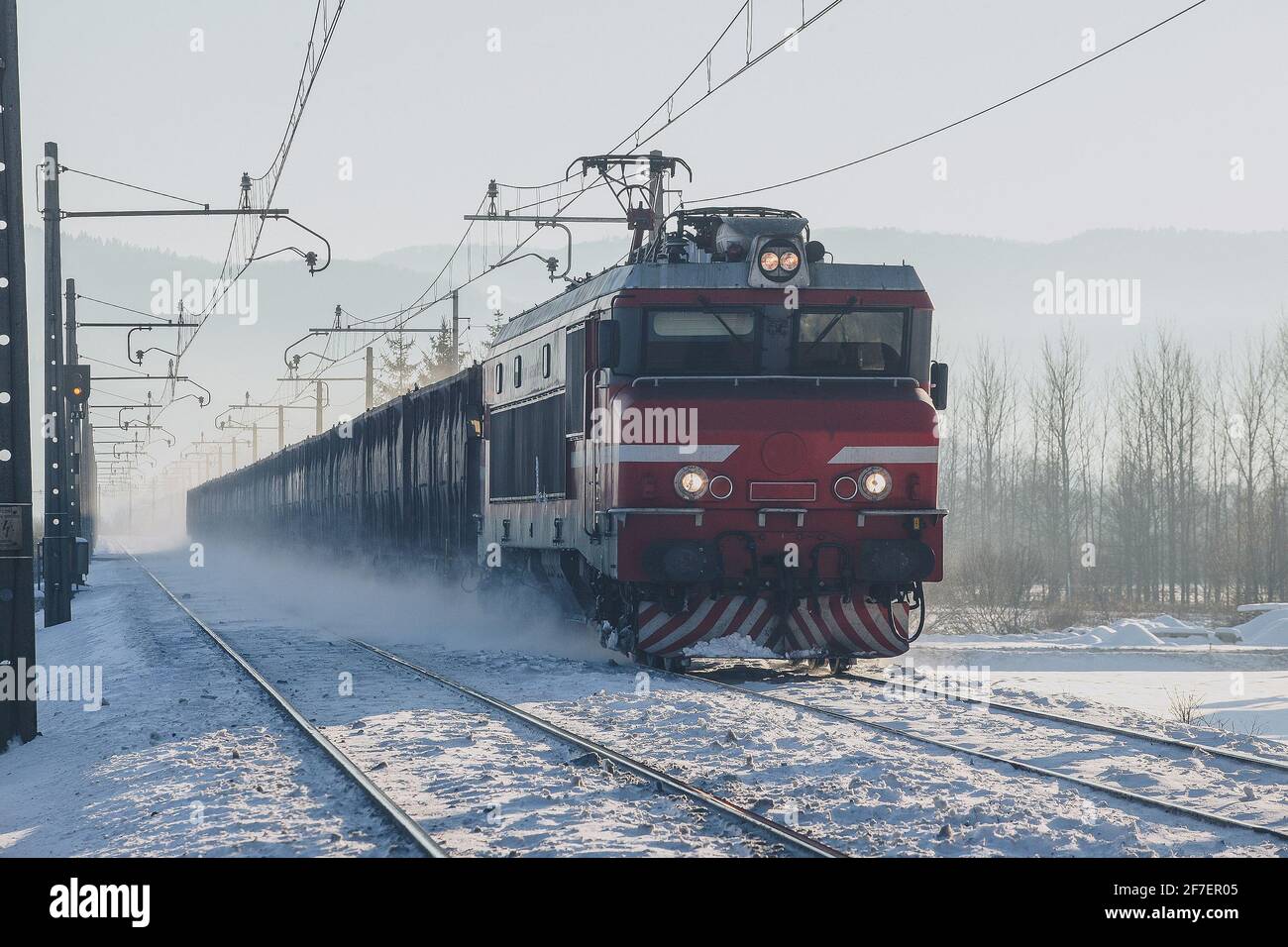 A train coming towards the camera on a snowy track with snow rising ...