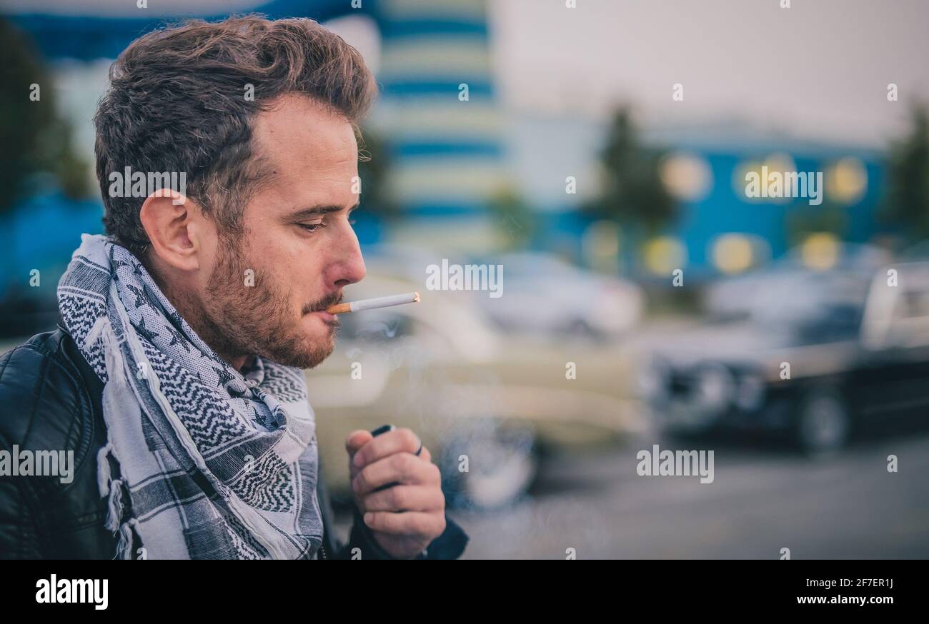 Hipster looking young caucasian man lighting up a cigarette and smoking ...